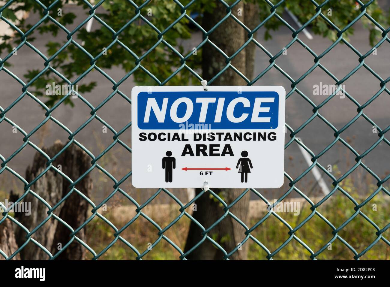 blue and white sign says NOTICE social distancing area with male and ...
