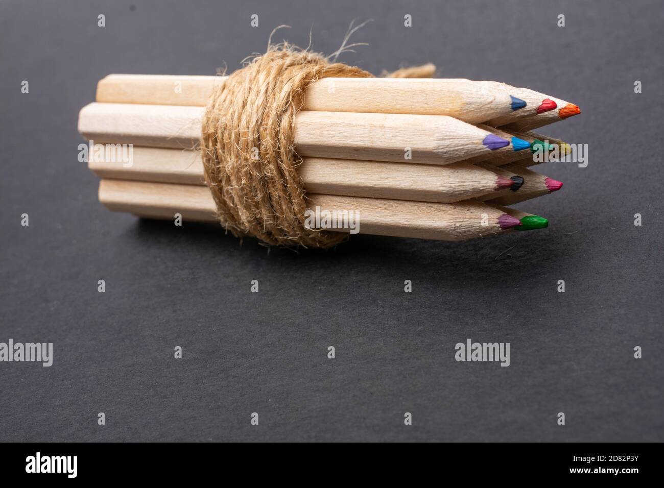 Bundle of colored pencils wrapped with string on black Stock Photo - Alamy