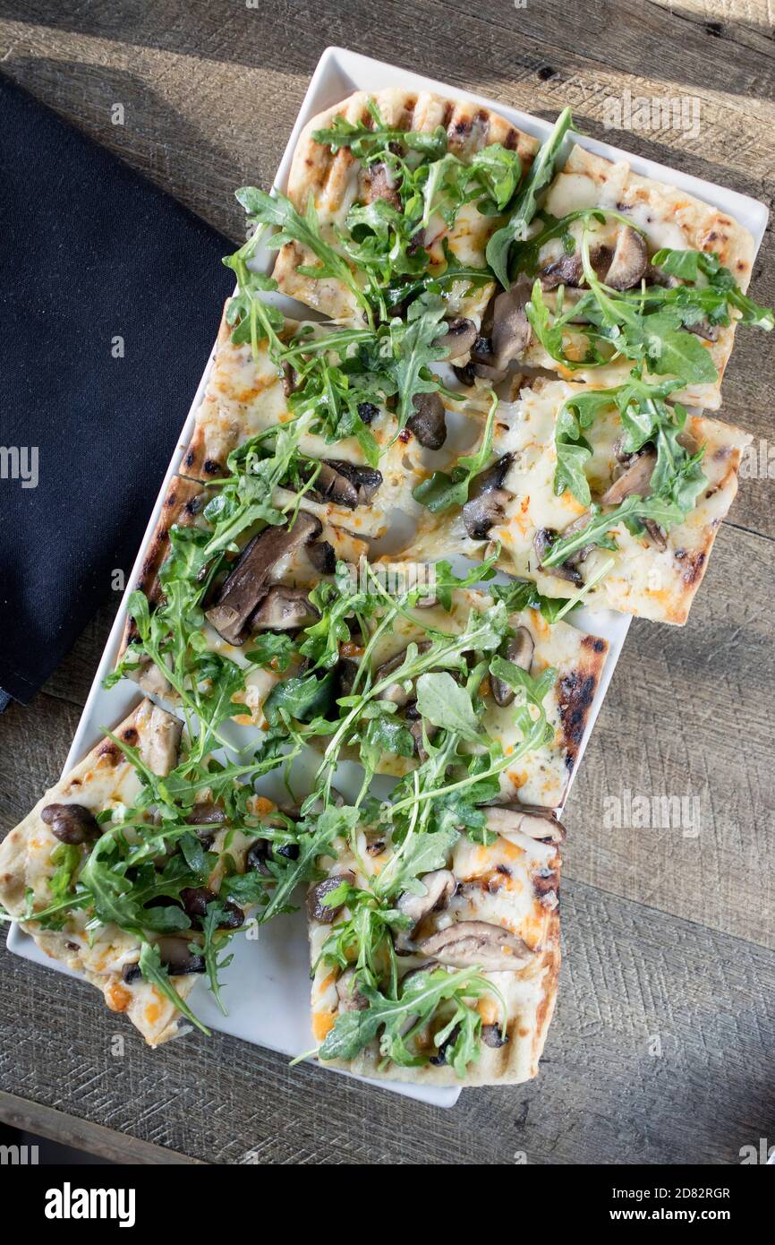 Personal flatbread pizza with wild mushrooms and arugula Stock Photo ...