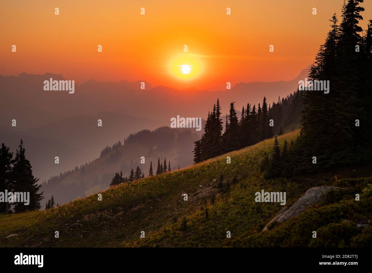 Bright orange sunset behind hazy cascade mountains with wildfire smoke ...