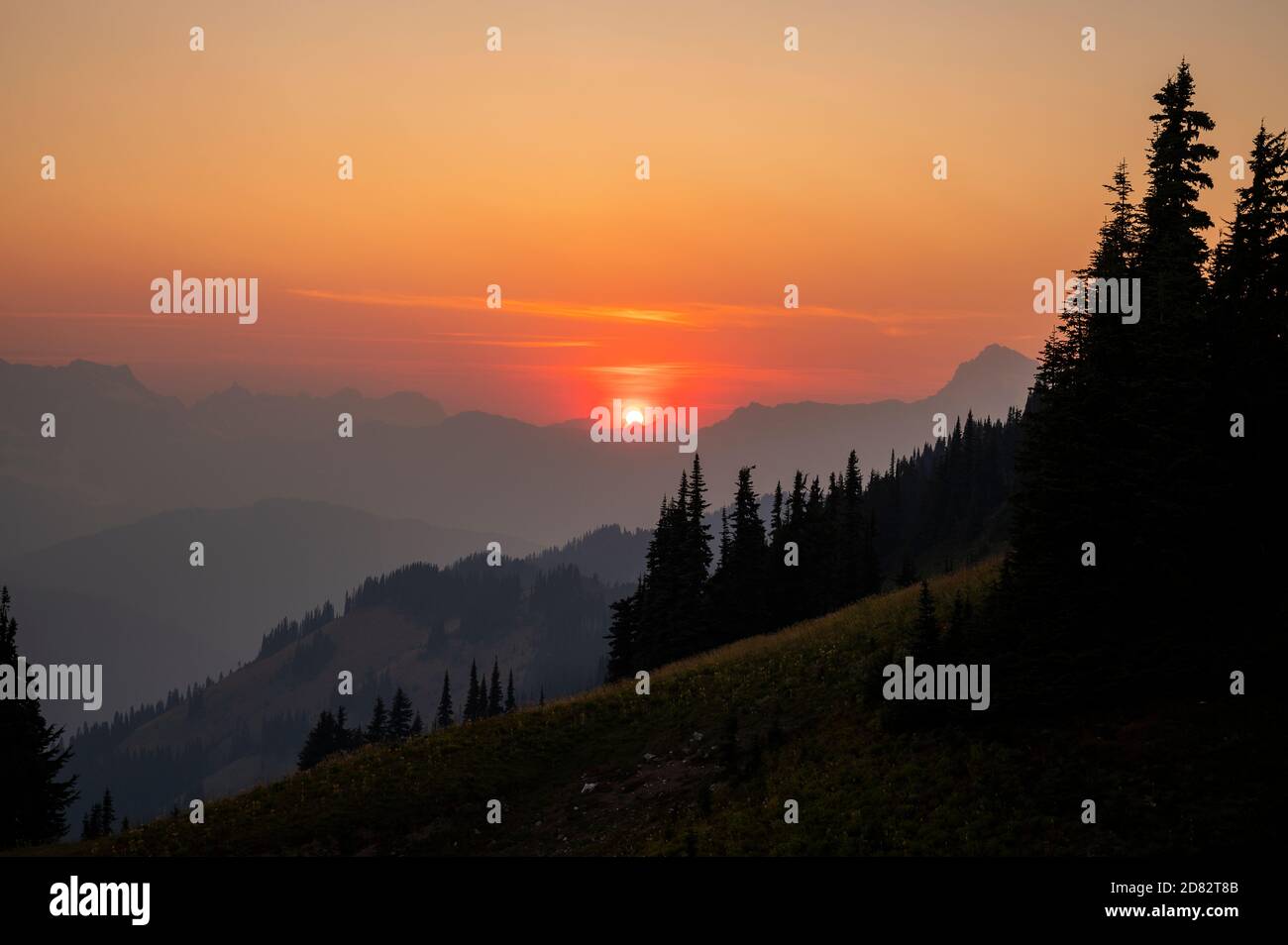 Sun going down behind the cascades with orange wildfire smoke sky Stock ...