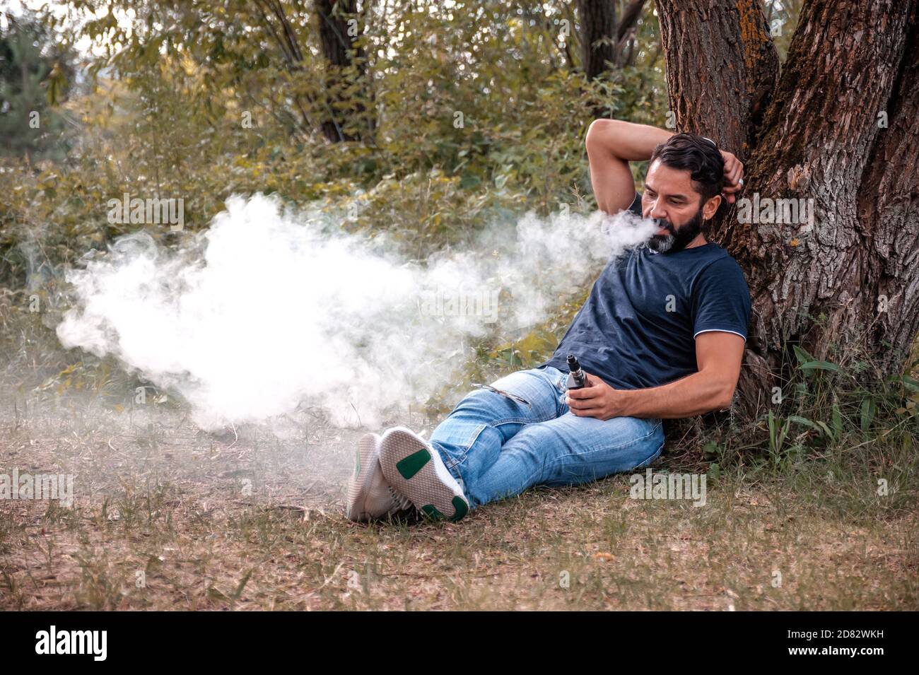 Stylish brutal smoker with beard and clouds of smoke looks relaxed ...