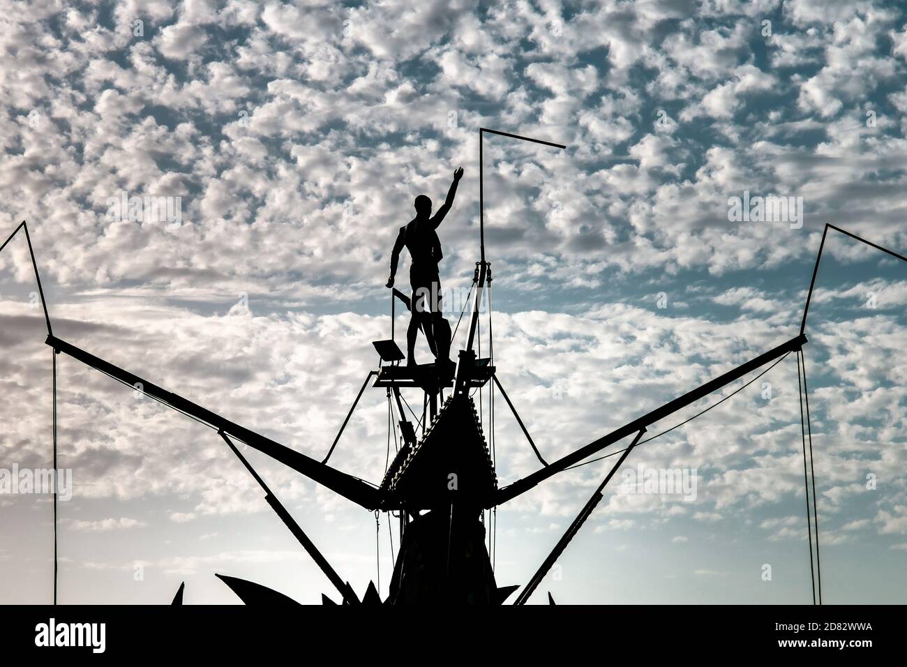 Backlit image of a figure in the top part of a fairground attraction ...