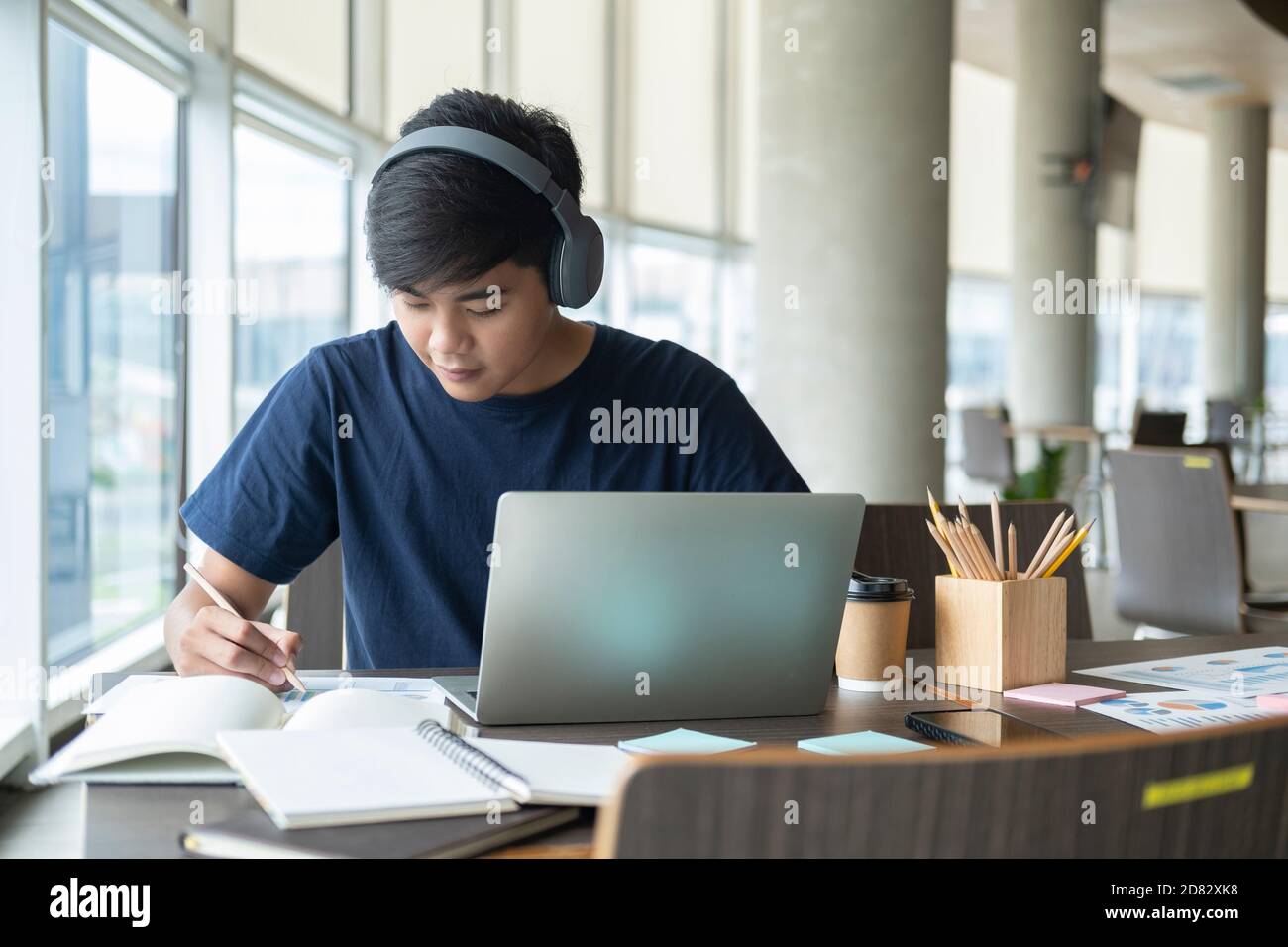 Young collage student using computer and mobile device studying online ...