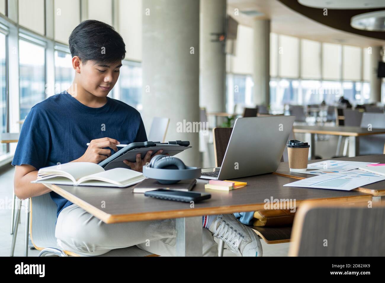 Young collage student using computer and mobile device studying online ...