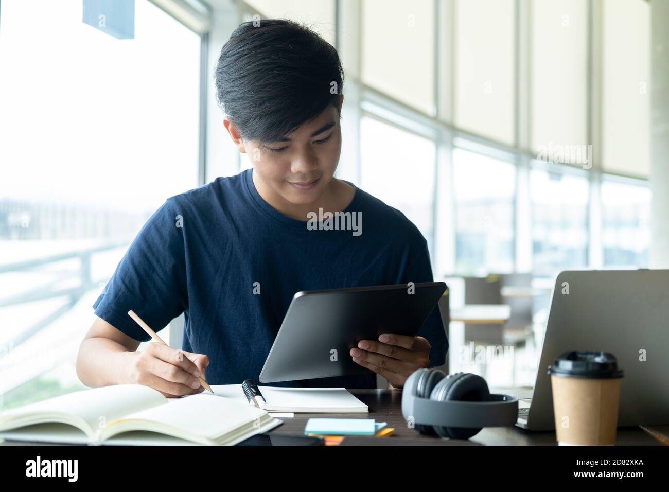 Young collage student using computer and mobile device studying online ...