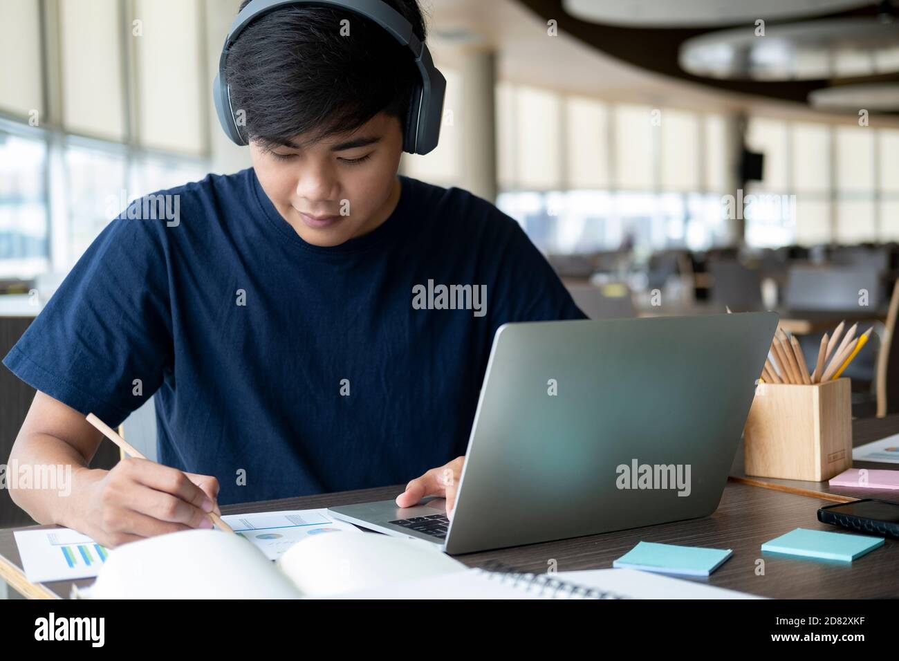 Young collage student using computer and mobile device studying online ...
