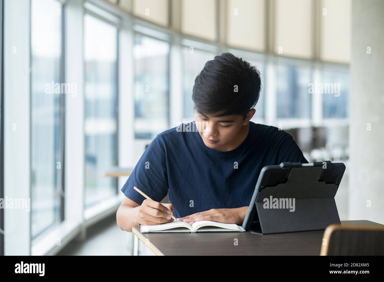 Young collage student using computer and mobile device studying online ...
