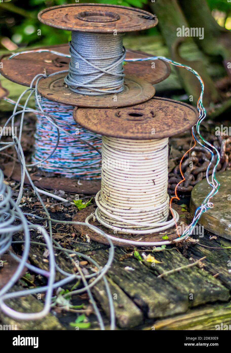 Three rusty spools hold coated wire for creative projects or industrial ...