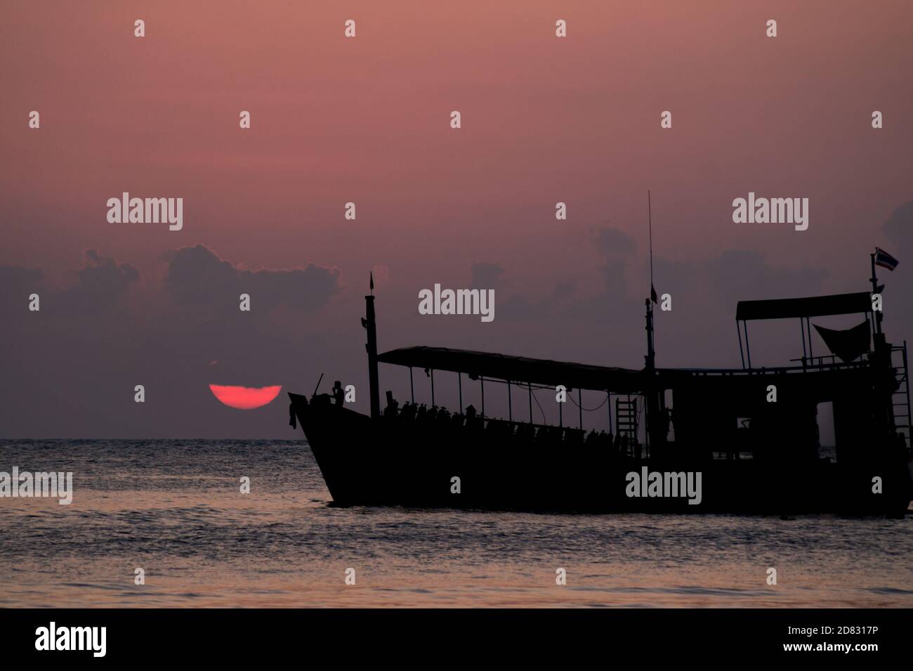 cargo ship at sunset with red sun Stock Photo - Alamy