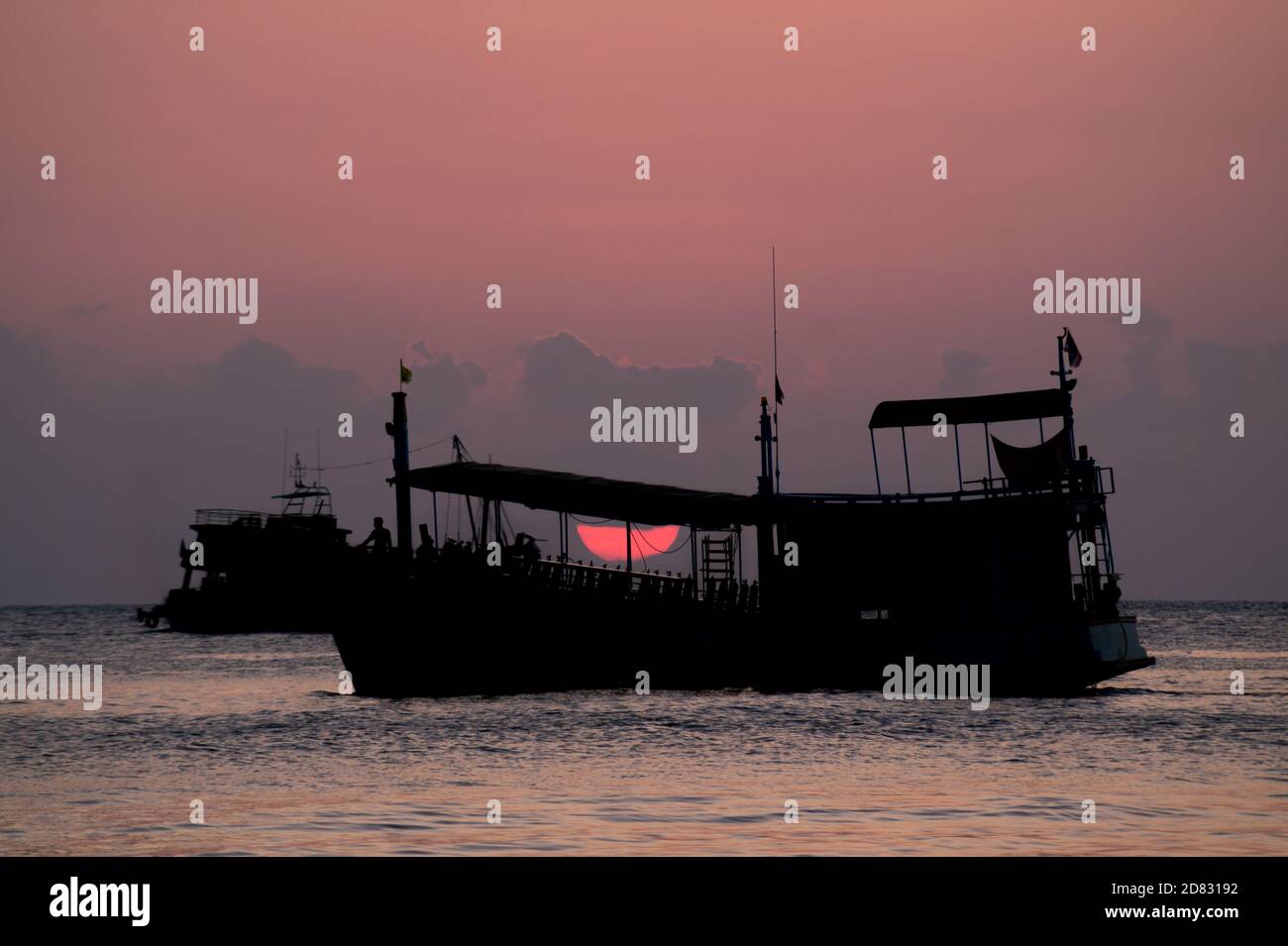 cargo ship at sunset with red sun Stock Photo - Alamy
