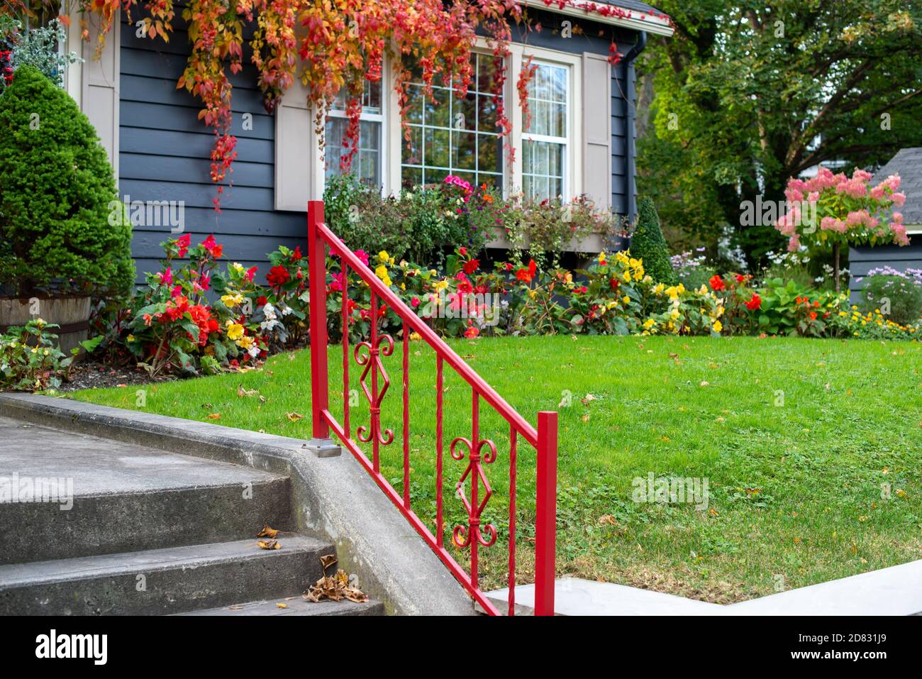 A bright red metal handrail leading up four concrete steps to a walkway ...