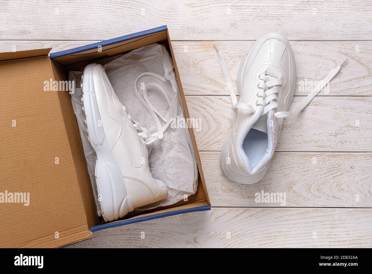 One white chunky sole sneakers in a brown cardboard box, the other on ...