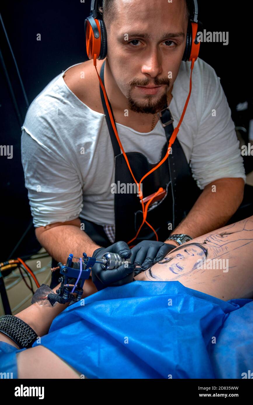 Master tattooist demonstrates the process of getting tattoo in tattoo ...