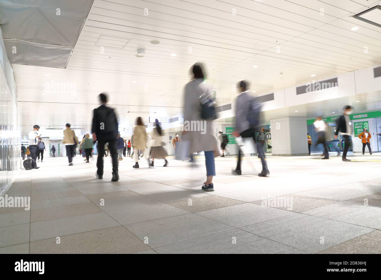 Pedestrians walk an underground walkway at JR Shinjuku Station in Tokyo ...