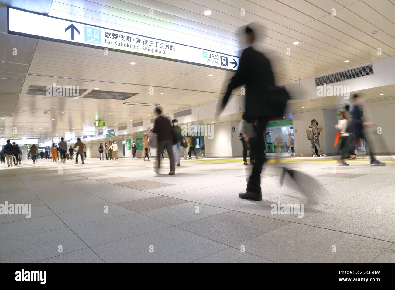 Pedestrians walk an underground walkway at JR Shinjuku Station in Tokyo ...