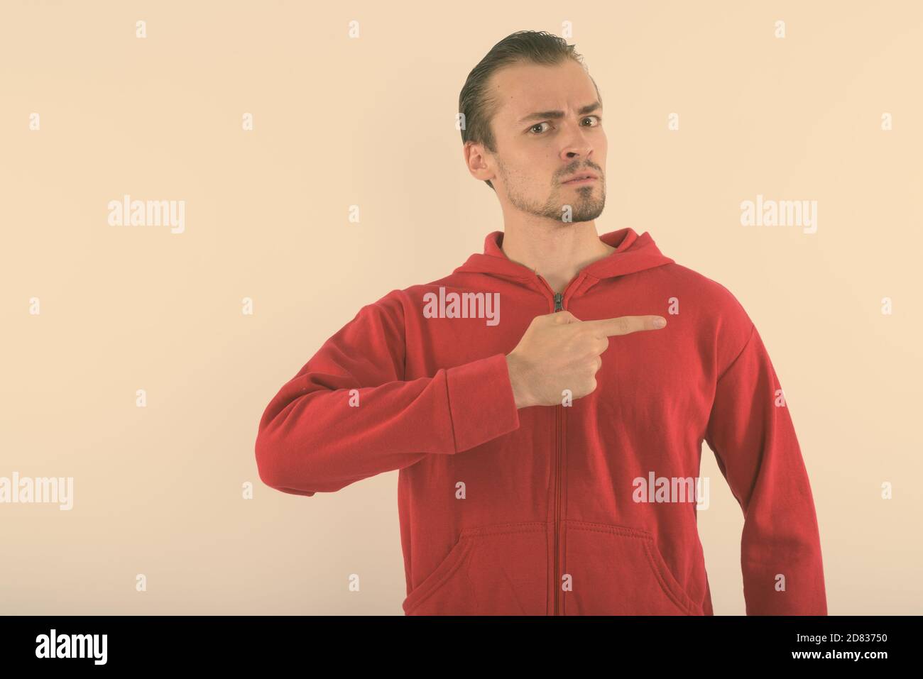 Studio shot of young angry bearded man pointing to the side against ...