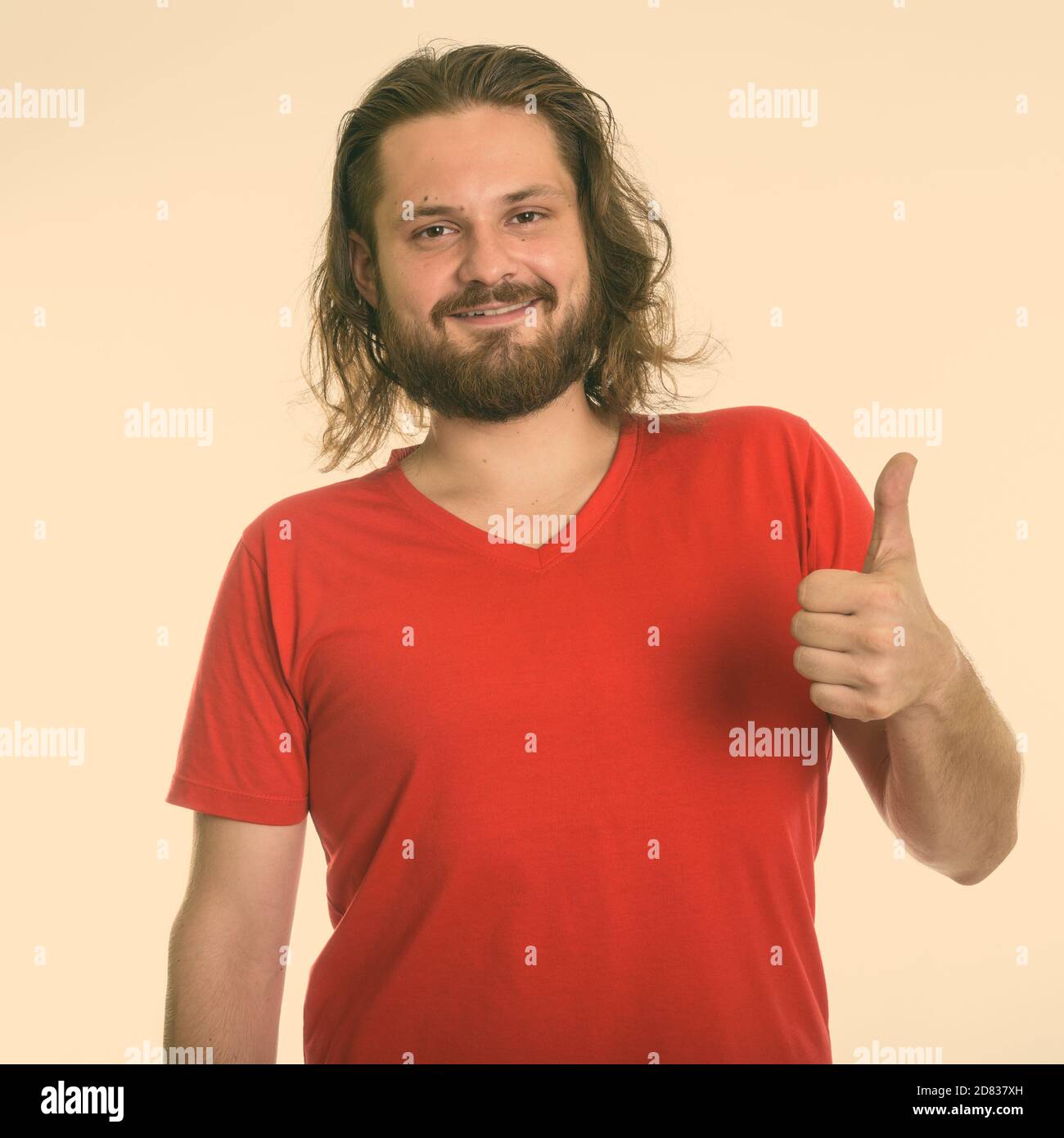 Studio shot of young happy bearded man smiling while giving thumb up ...