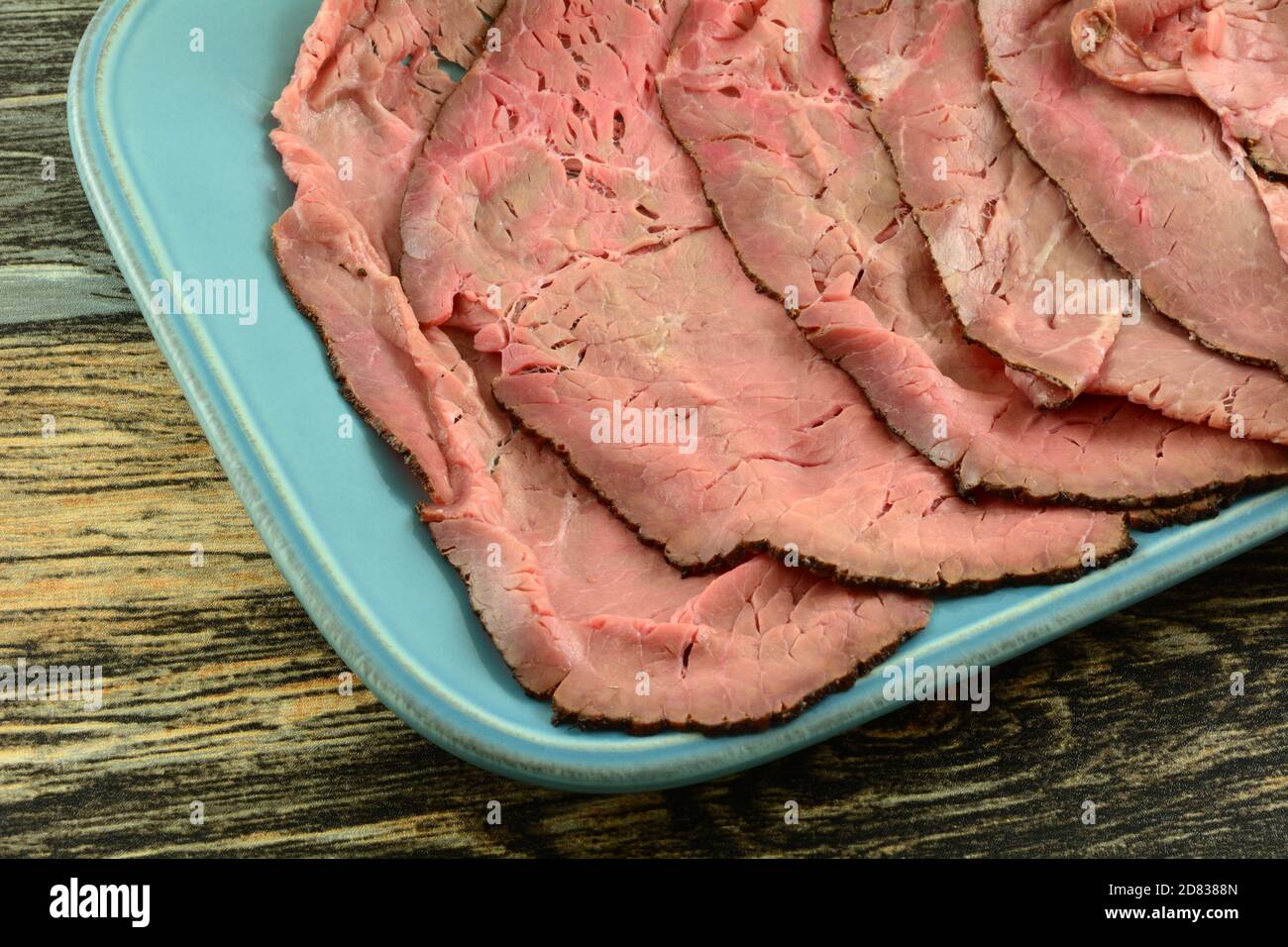 Rare London broil roast beef slices on blue serving platter Stock Photo ...