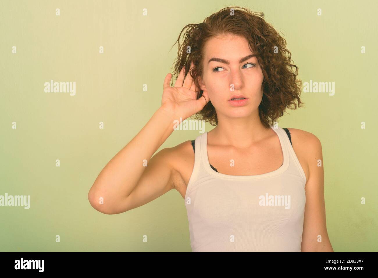 Studio shot of beautiful teenage girl thinking while listening against ...