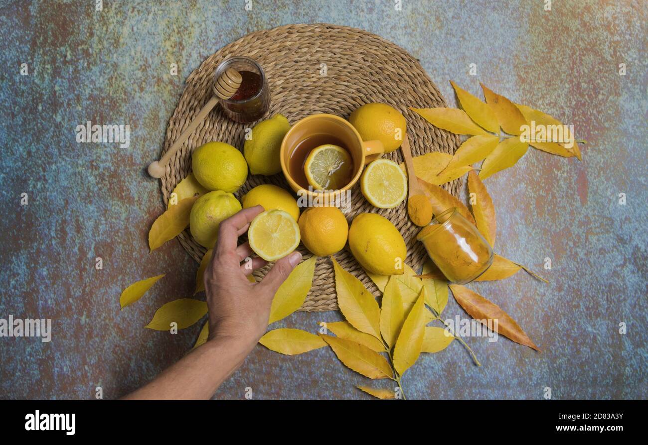 Human hand picking up half a lemon, still life of lemons, turmeric and ...