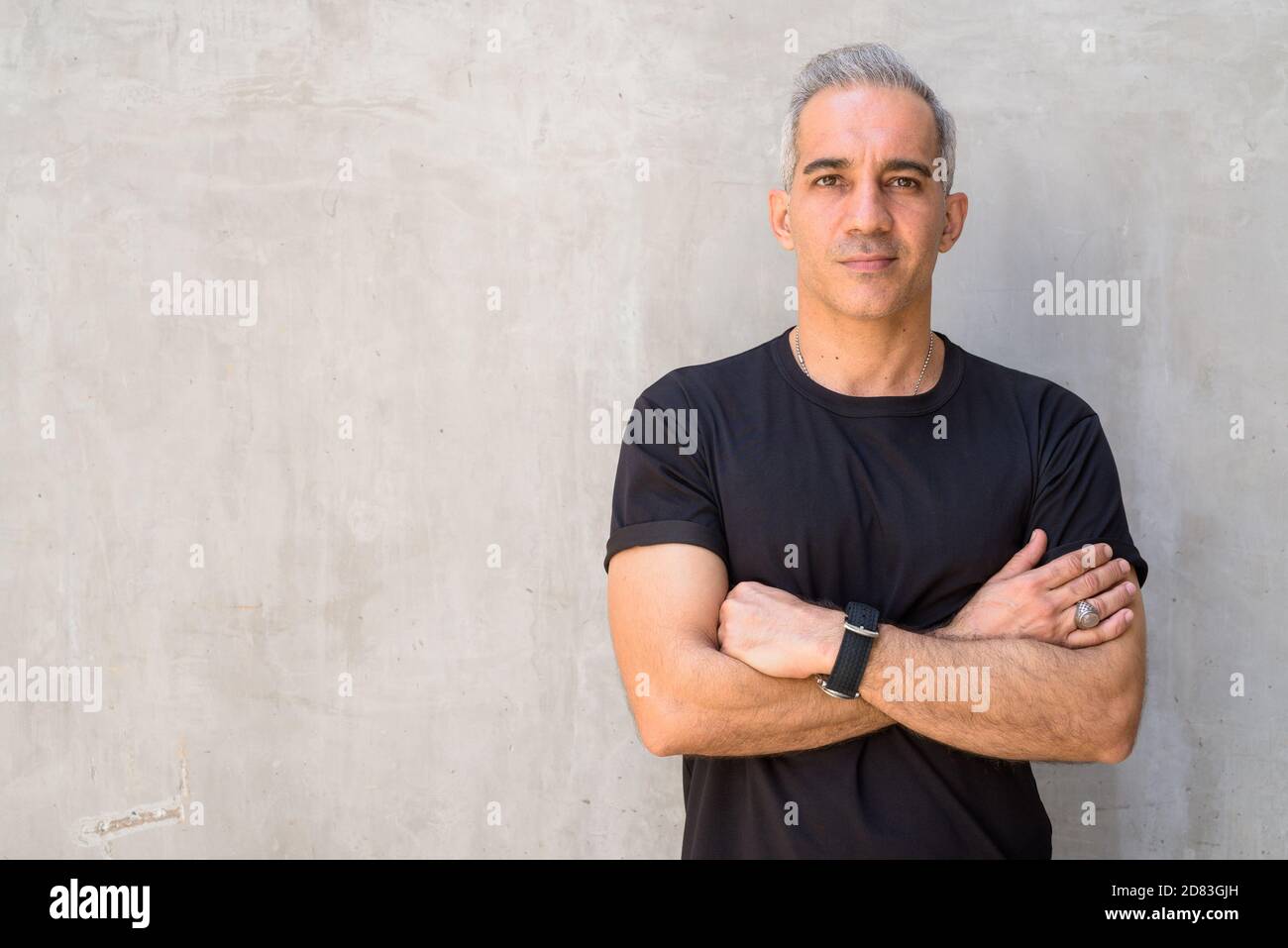 Handsome Persian man with arms crossed against concrete wall Stock ...