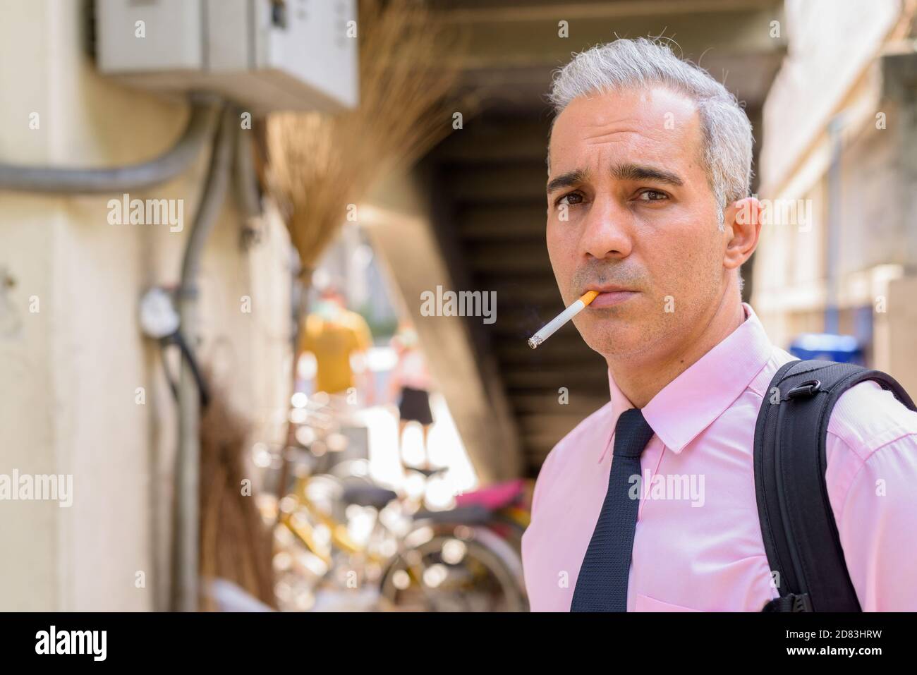 Face of Persian businessman with gray hair smoking cigarette in the ...