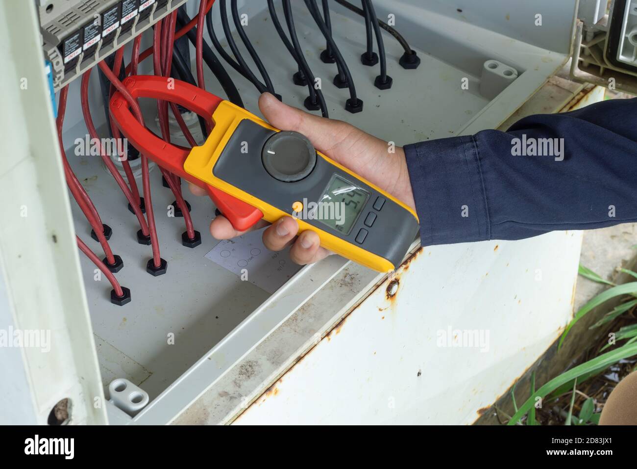 Workers use Clamp meter to measure the current of electrical wires ...
