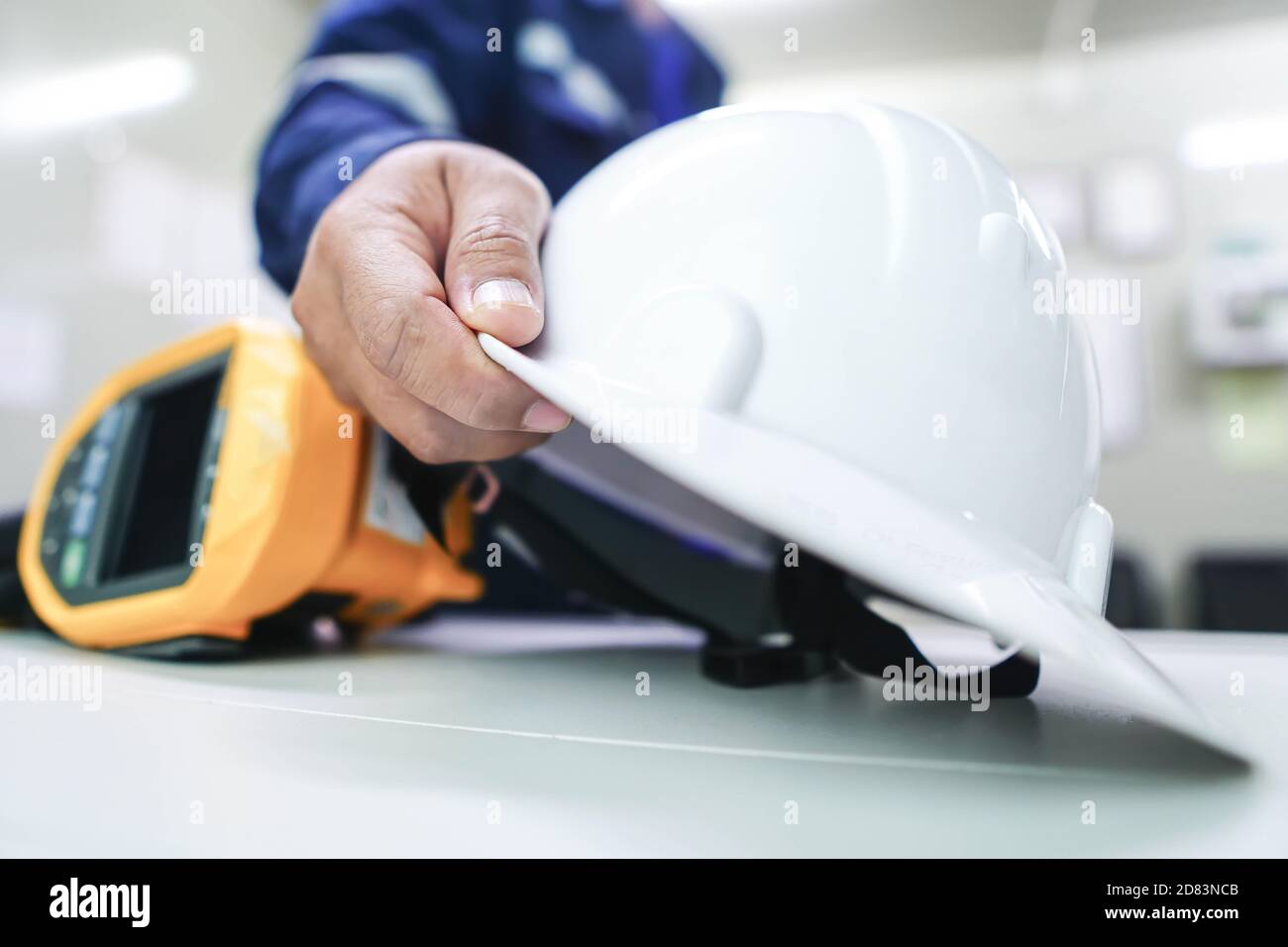 The engineer picks up the white helmet placed on the office desk with a ...
