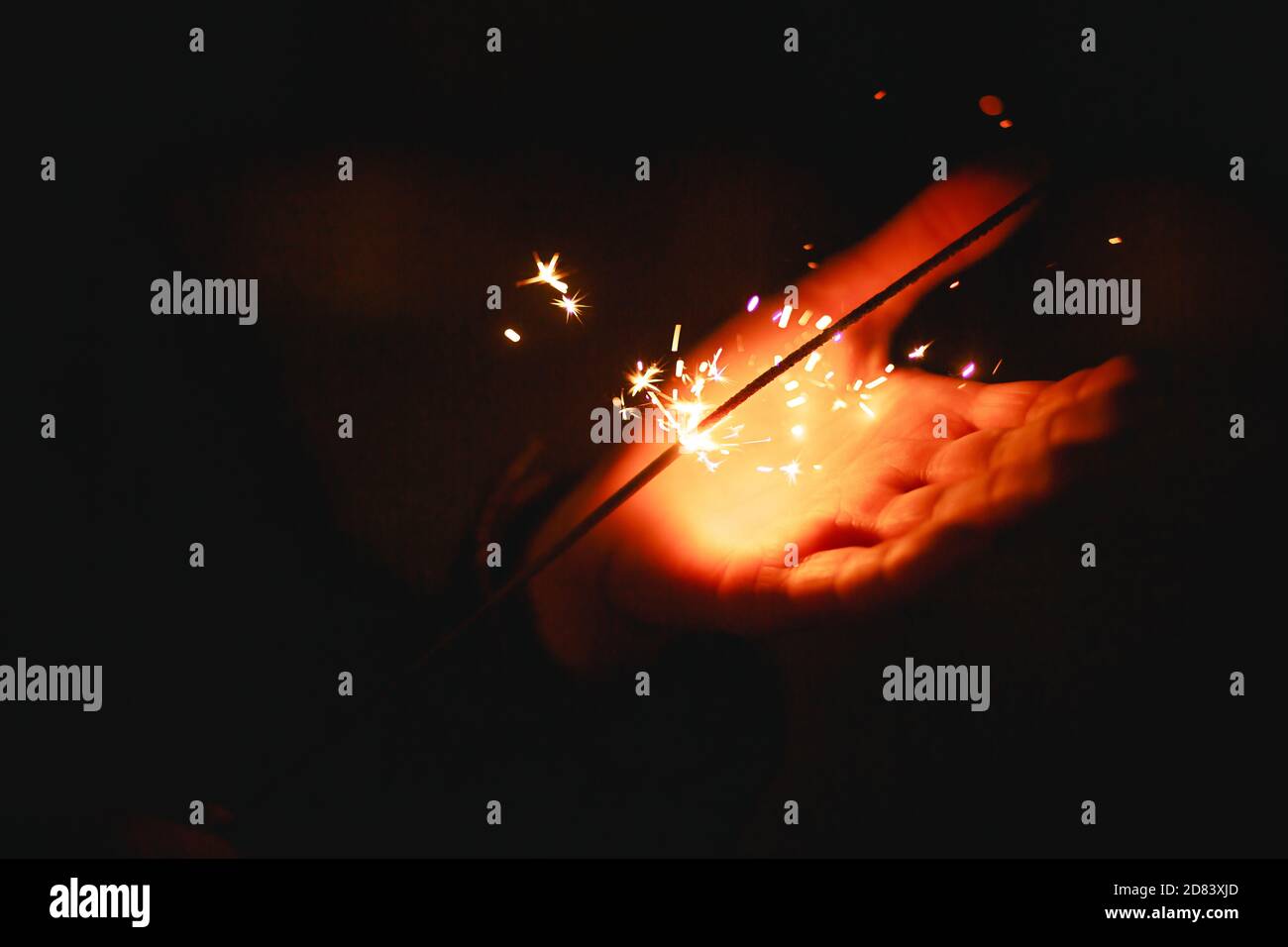 Sparks and light from sparklers in the dark on the palm of a person ...