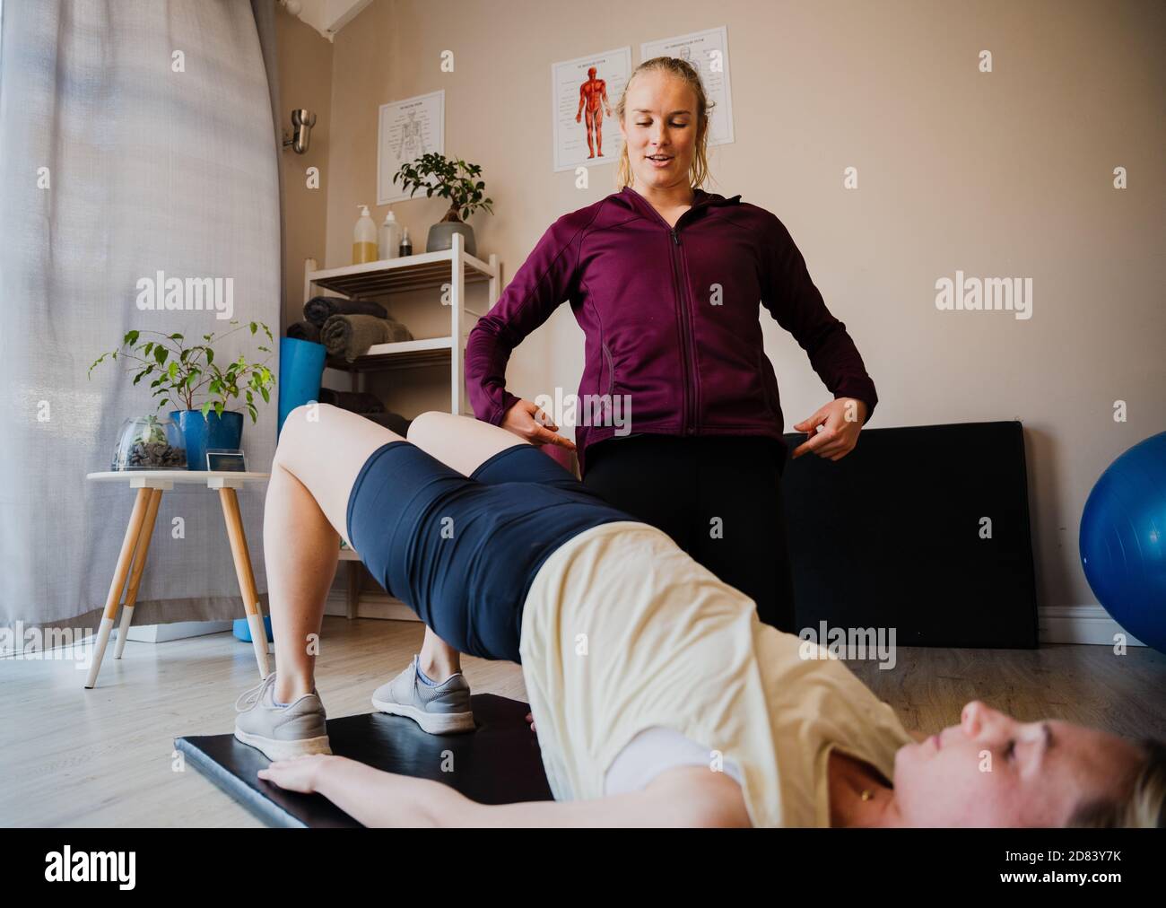 physio-therapist corrects alignment of patient attempting bridge ...