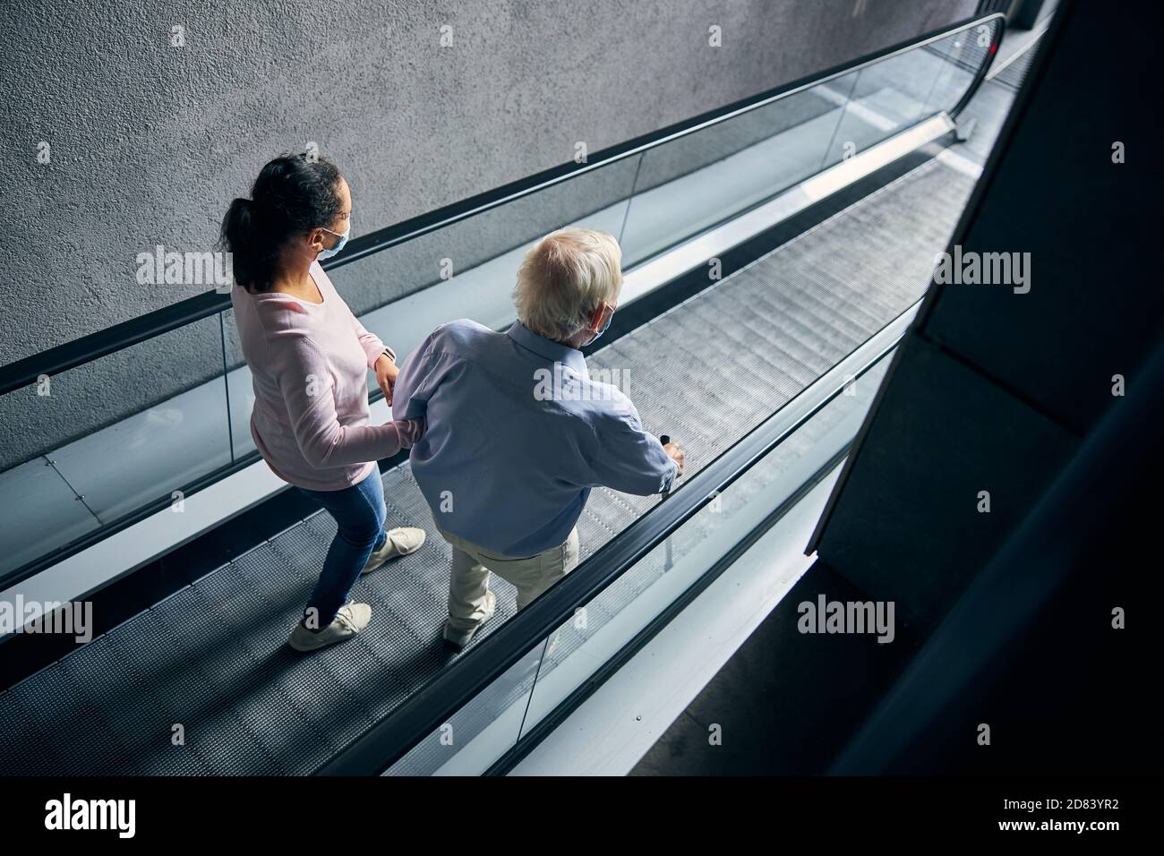 Woman and old man moving on escalator to the exit Stock Photo - Alamy