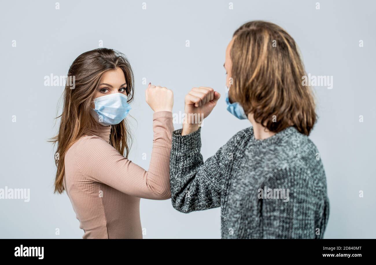 Elbows bump. Friends in protective medical mask on his face greet their ...