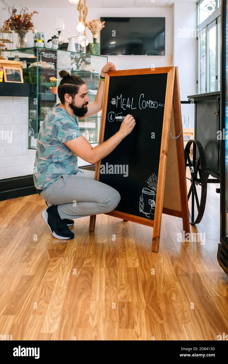 Young waiter writing the daily menu Stock Photo - Alamy