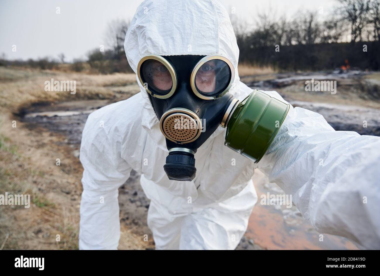 Close-up snapshot of scientist in gas mask and coverall looking right ...