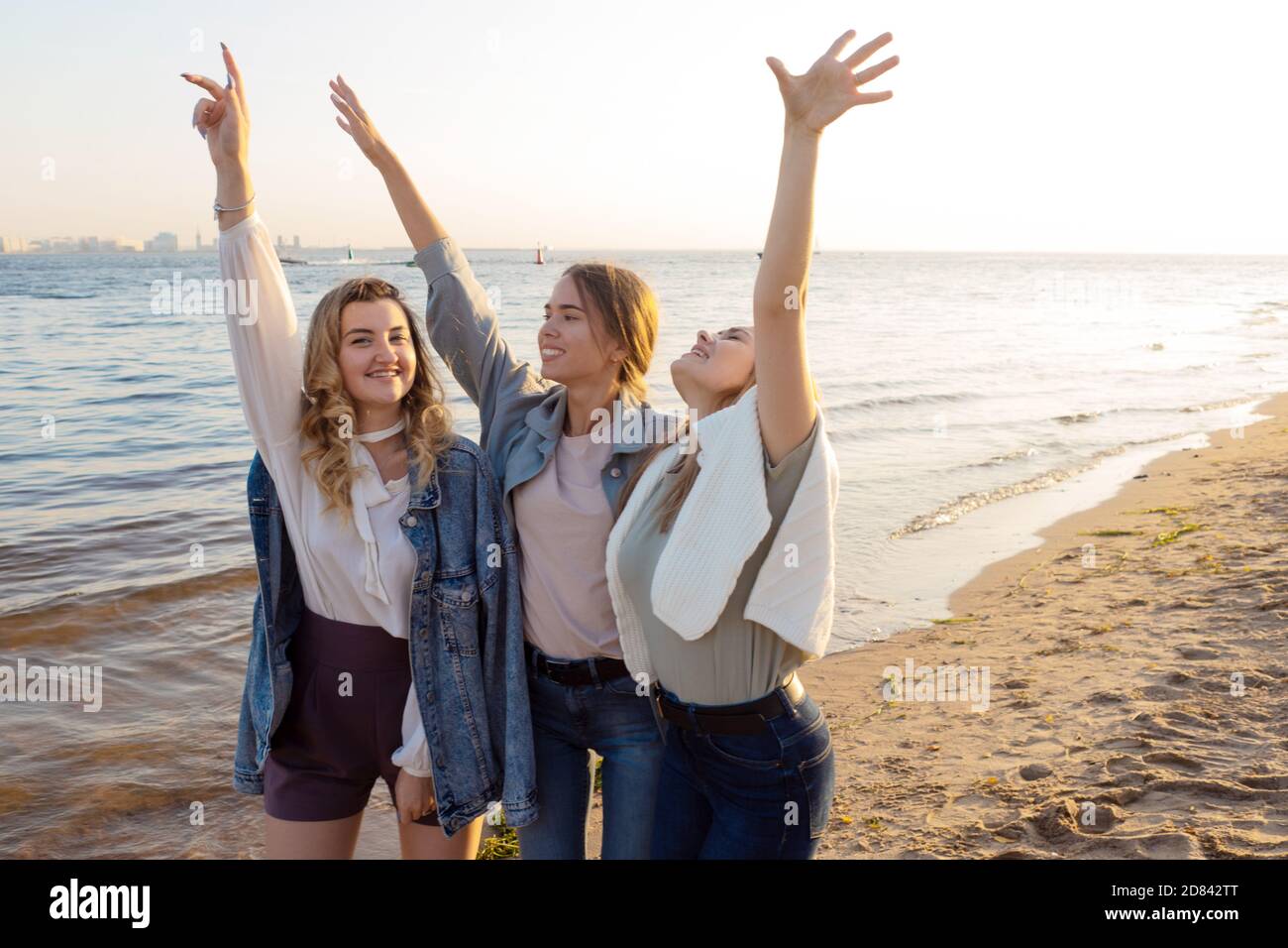Three friends having fun on the beach, meeting friends. Young women in ...