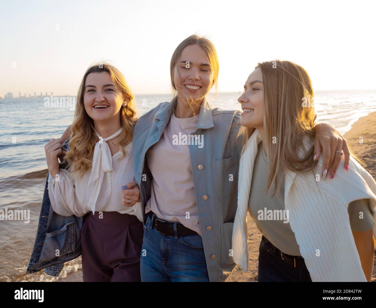 Three friends having fun on the beach, meeting friends. Young women in ...