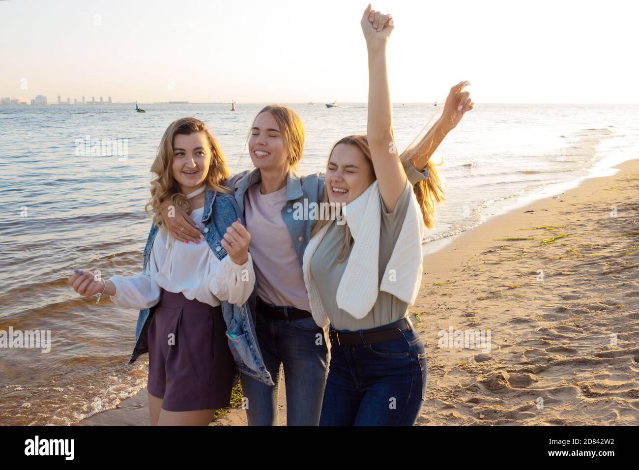 Three friends having fun on the beach, meeting friends. Young women in ...