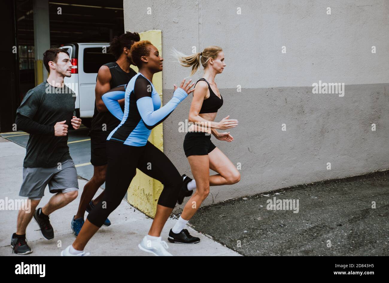 Group of urban runners running on the street in New york city ...