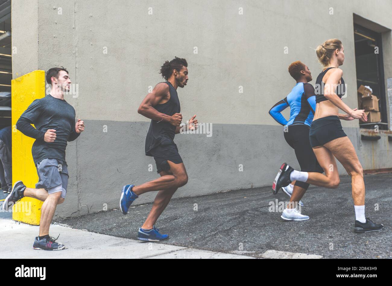Group of urban runners running on the street in New york city ...