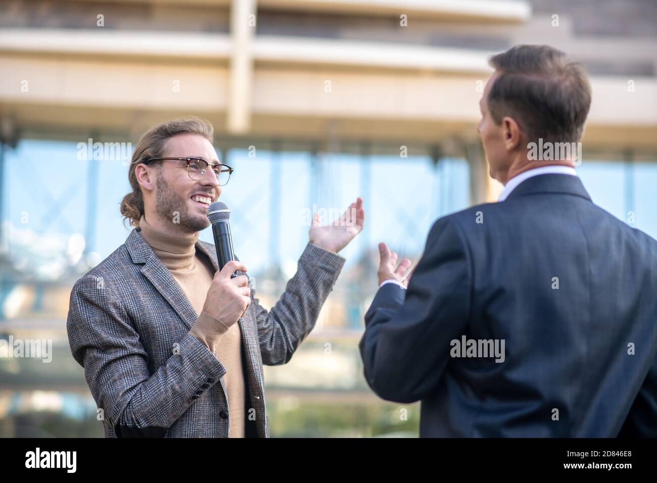 Fair-haired male journalist having interview with mature male outside Stock Photo - Alamy