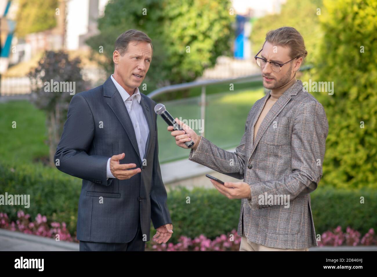 Male journalist taking taking inteview with mature man, recording it ...