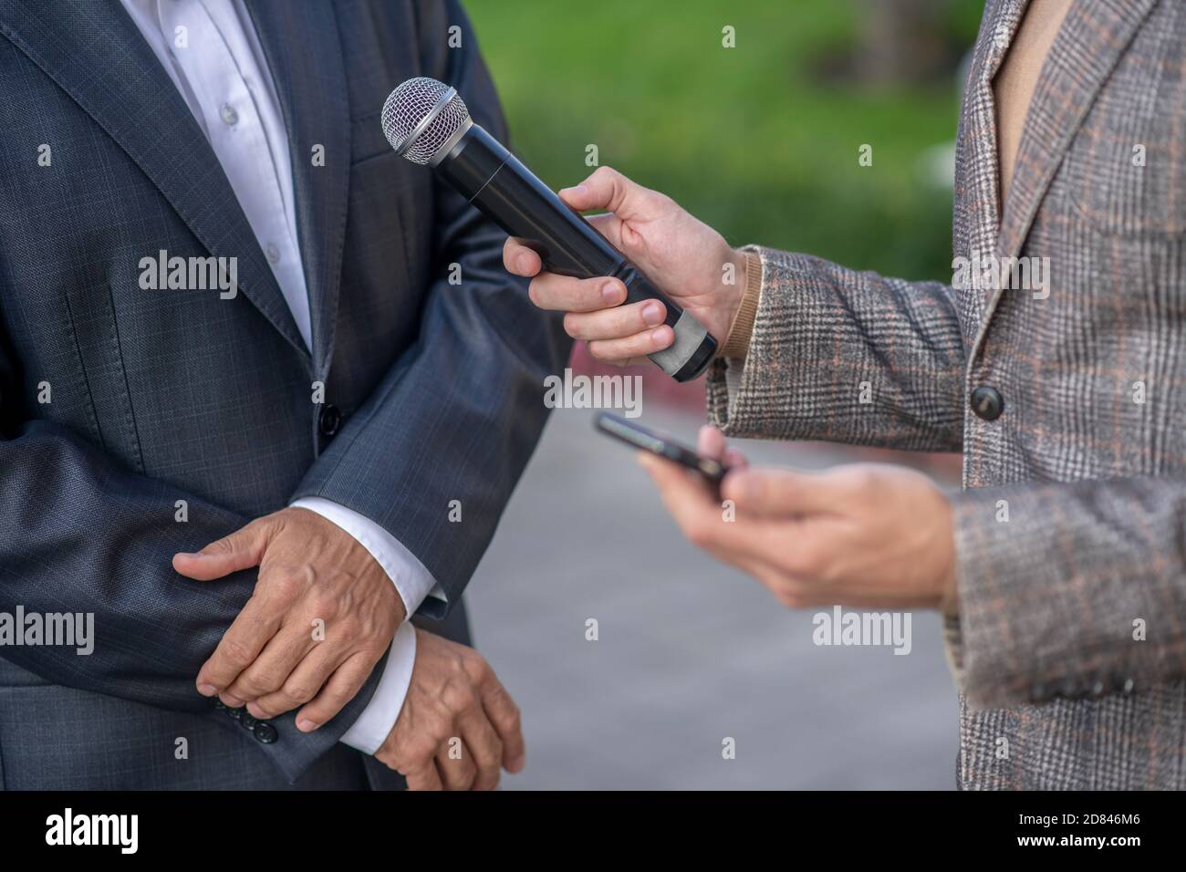 Close-up of male hands holding microphone and smartphone, recording ...