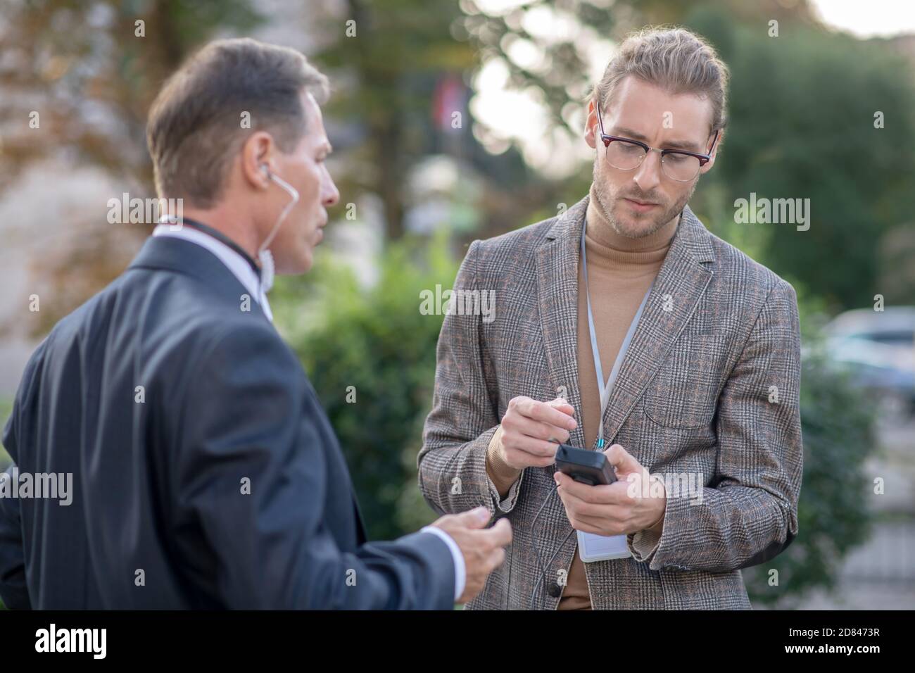 Fair-haired male journalist helping his collegue with headset Stock ...
