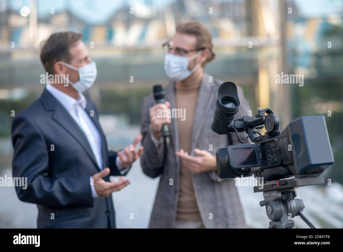 Male journalist interviewing mature male in front of camera, both ...