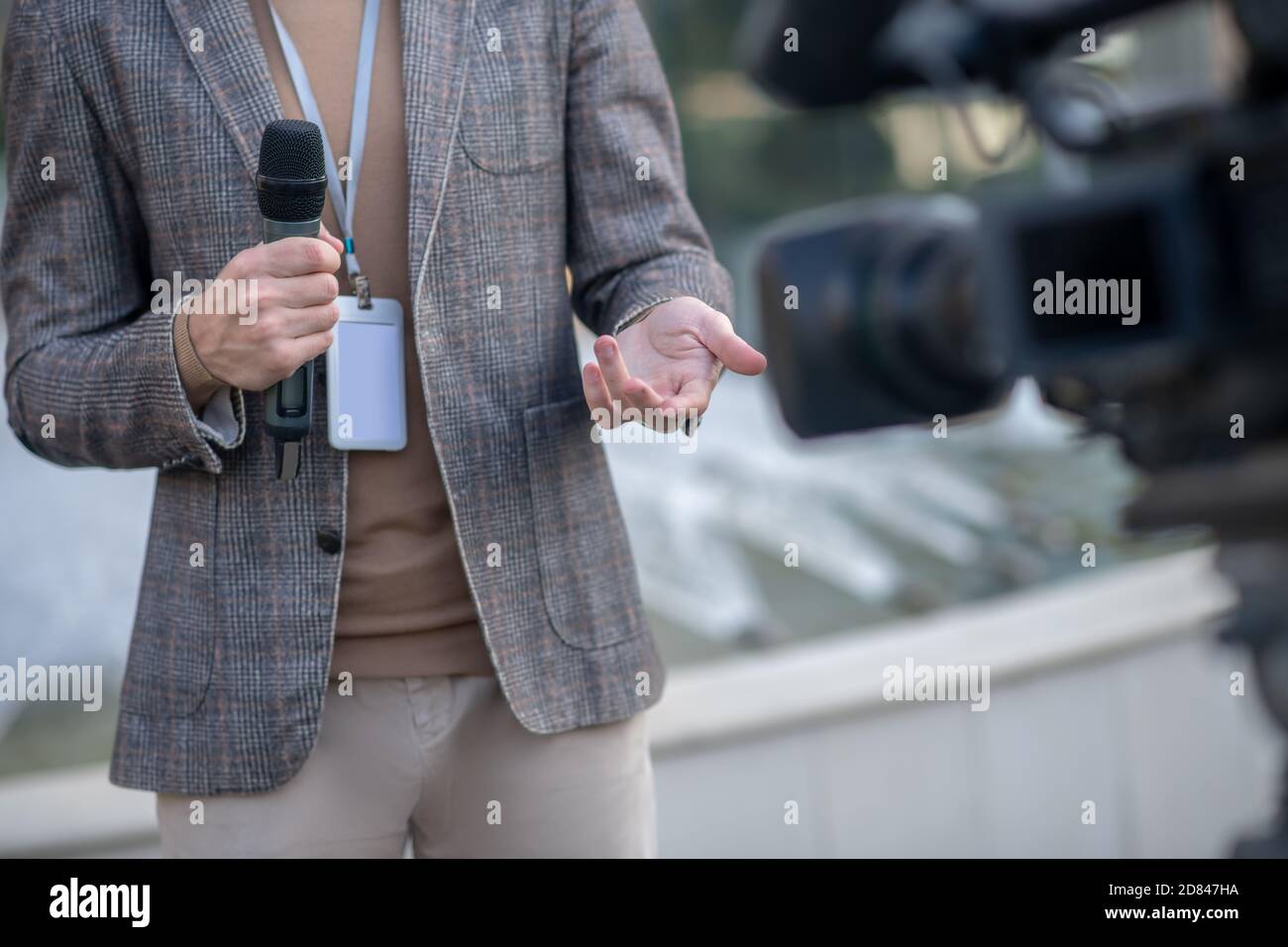 Close-up of male reporter hands holding microphone in front of camera ...