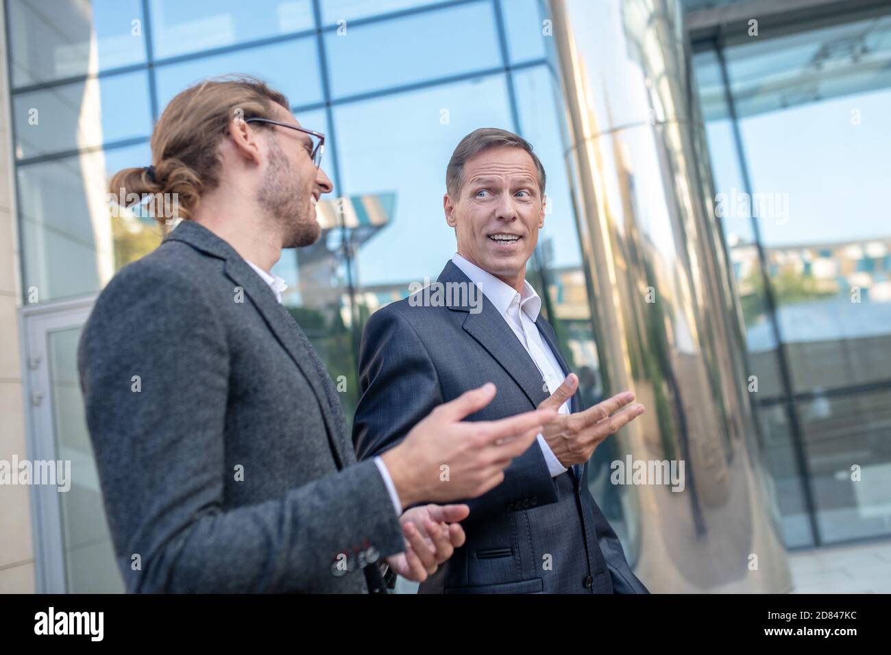 Two smiling male coworkers having friendly conversation outside Stock ...