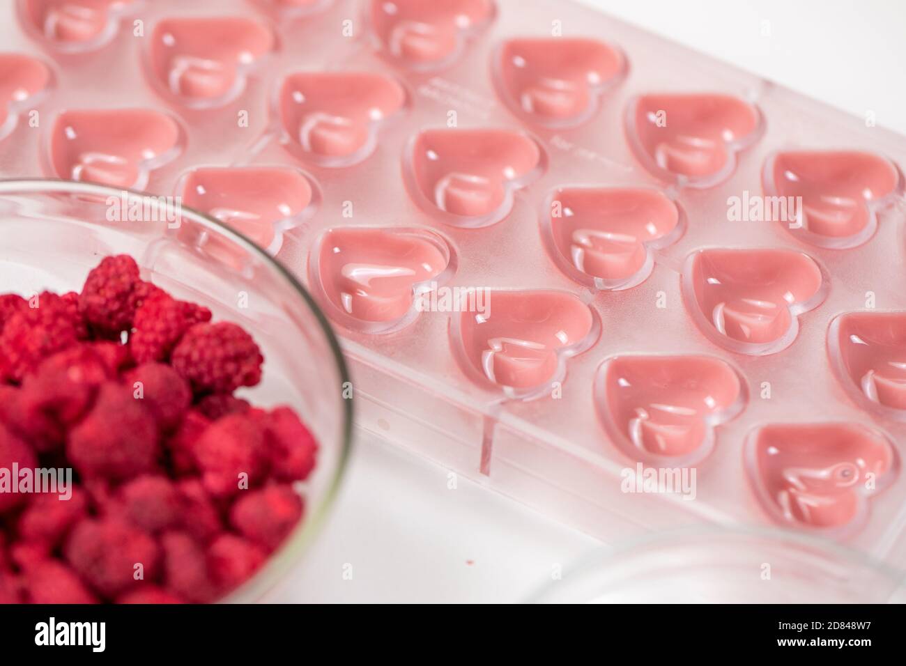 Heart shape confectionery mold with melted ruby chocolate and dried ...