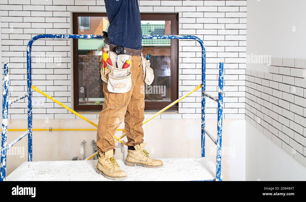 Electrician Builder at work, installation of lamps at height ...