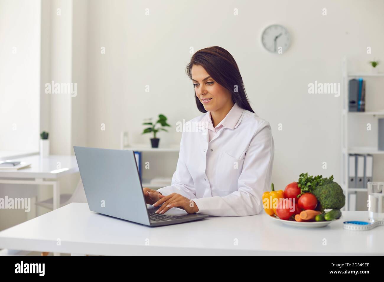 Dietitian using laptop making diet plan or giving consultation for ...